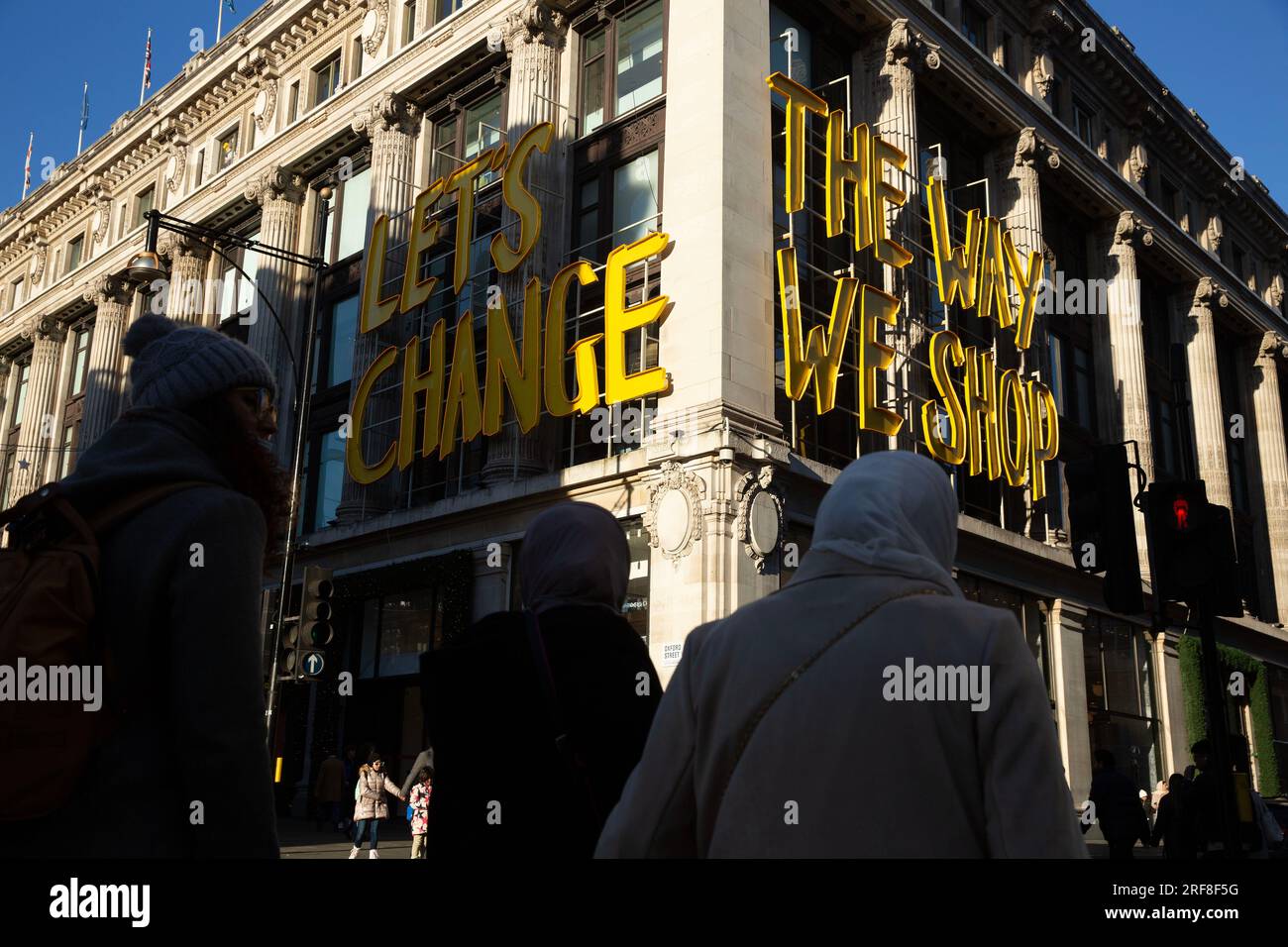 People are silhouetted against Selfridges store on Oxford Street in ...