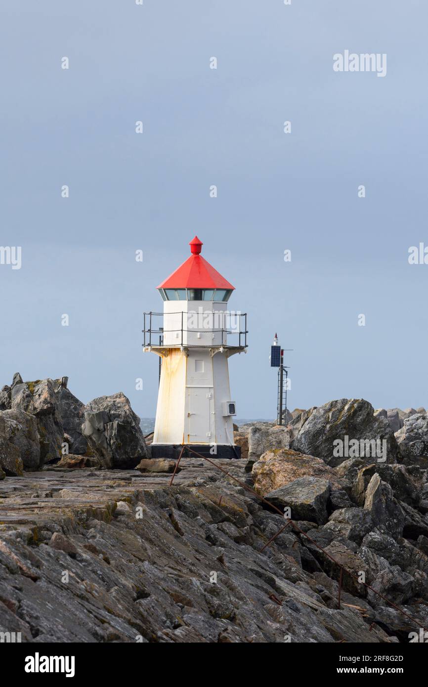 Small white and red lighthouse at the end of a quay wall against the ...