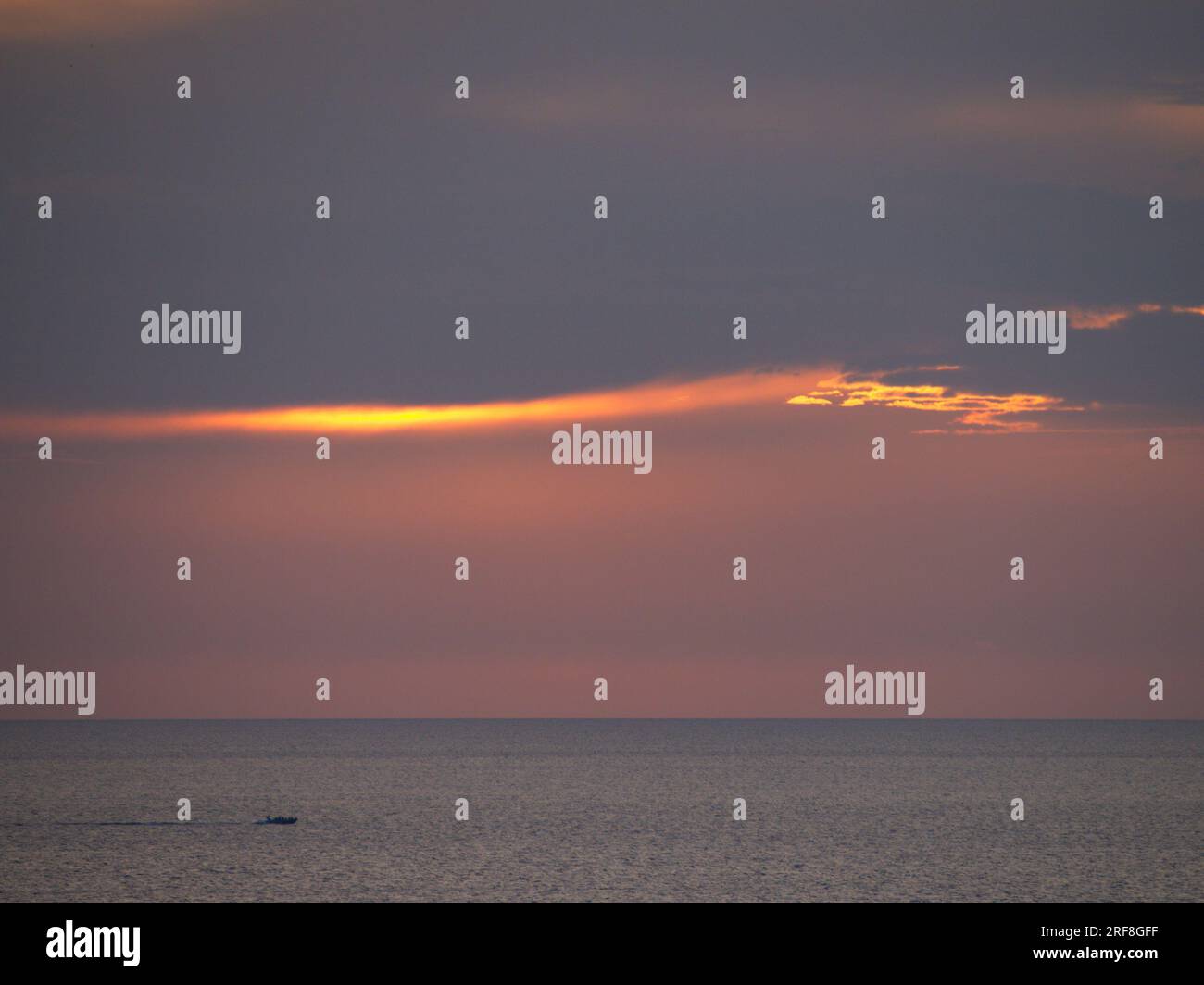 At sunset a ship sails in the distance.al atardecer un barco navega a ...