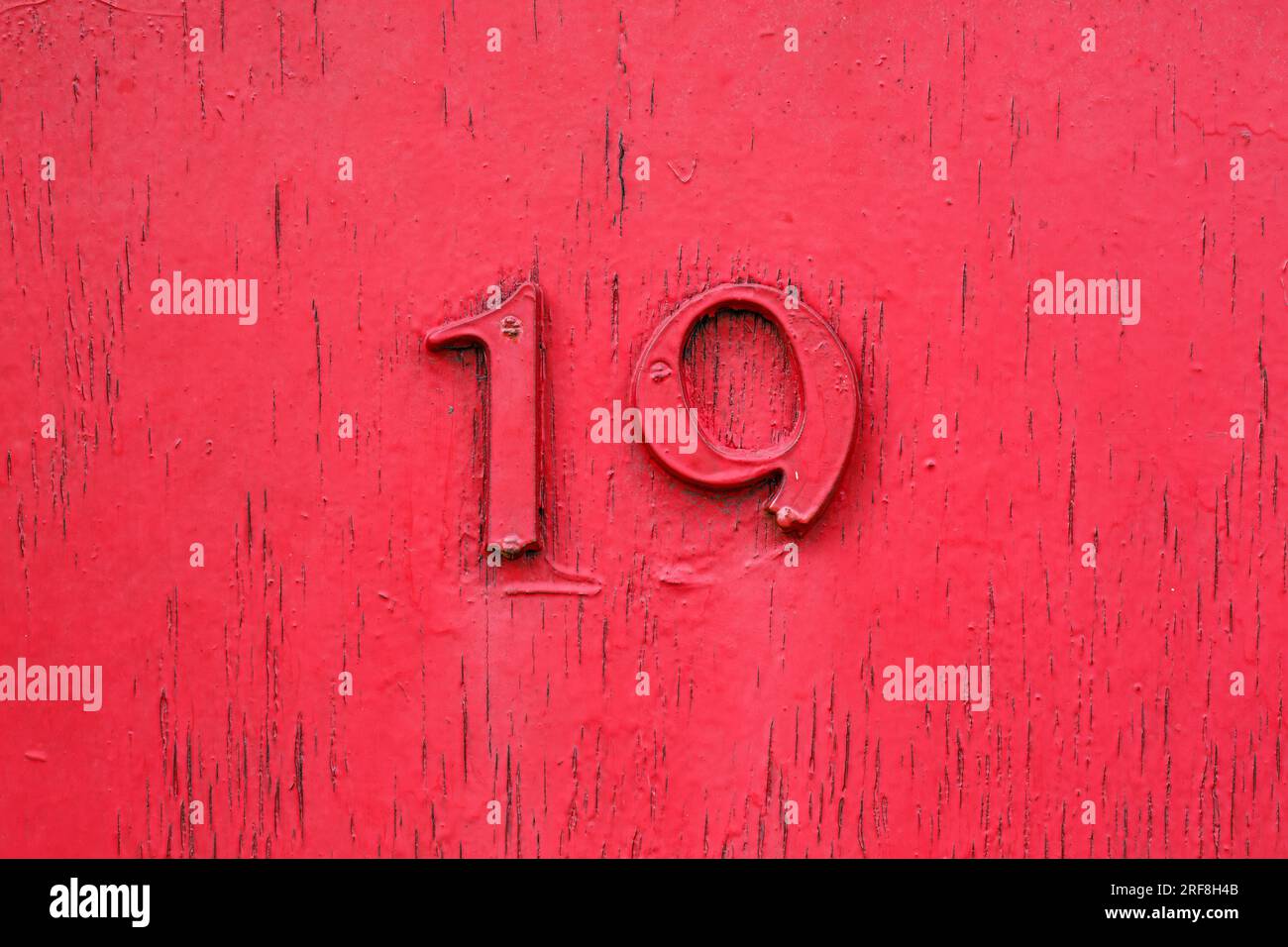 A broken house number nineteen painted red Stock Photo - Alamy