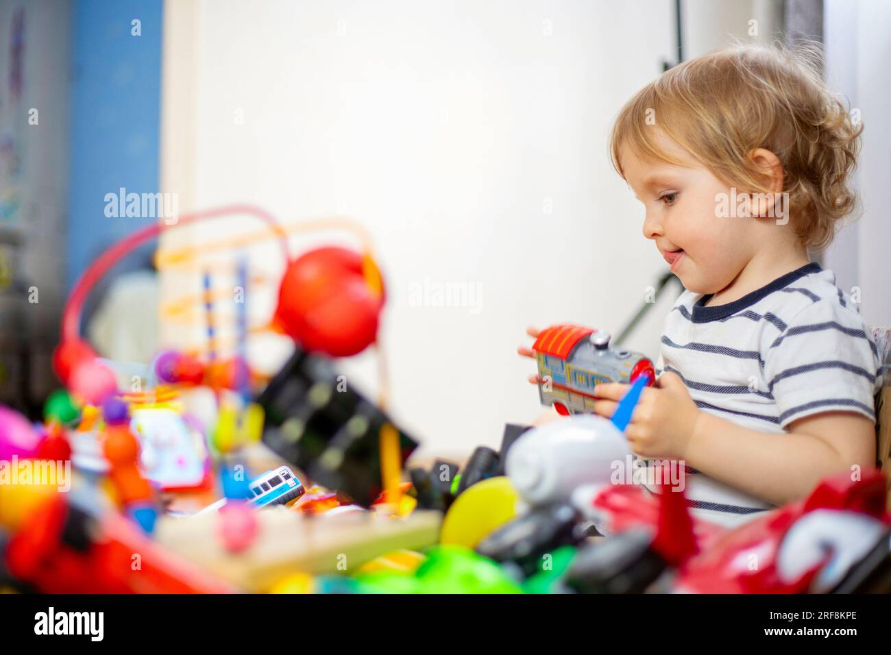 A huge bunch of different and colored toys in front of playful child ...
