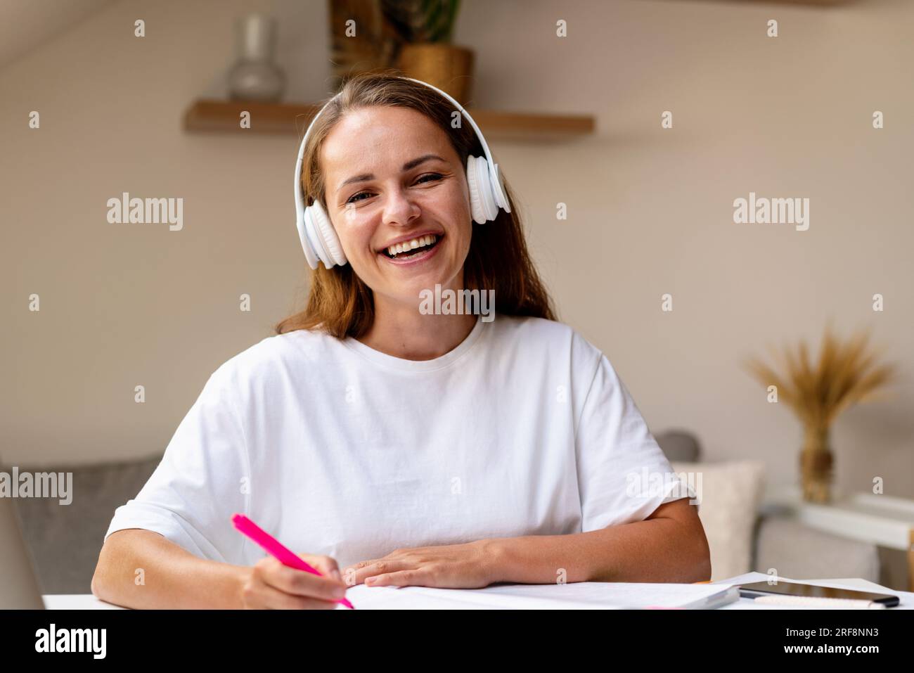 Front view portrait of young laughing female student in headphones ...