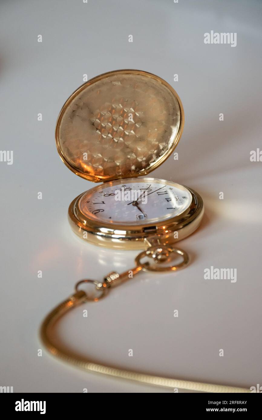 A vintage gold pocket watch on a white table Stock Photo - Alamy