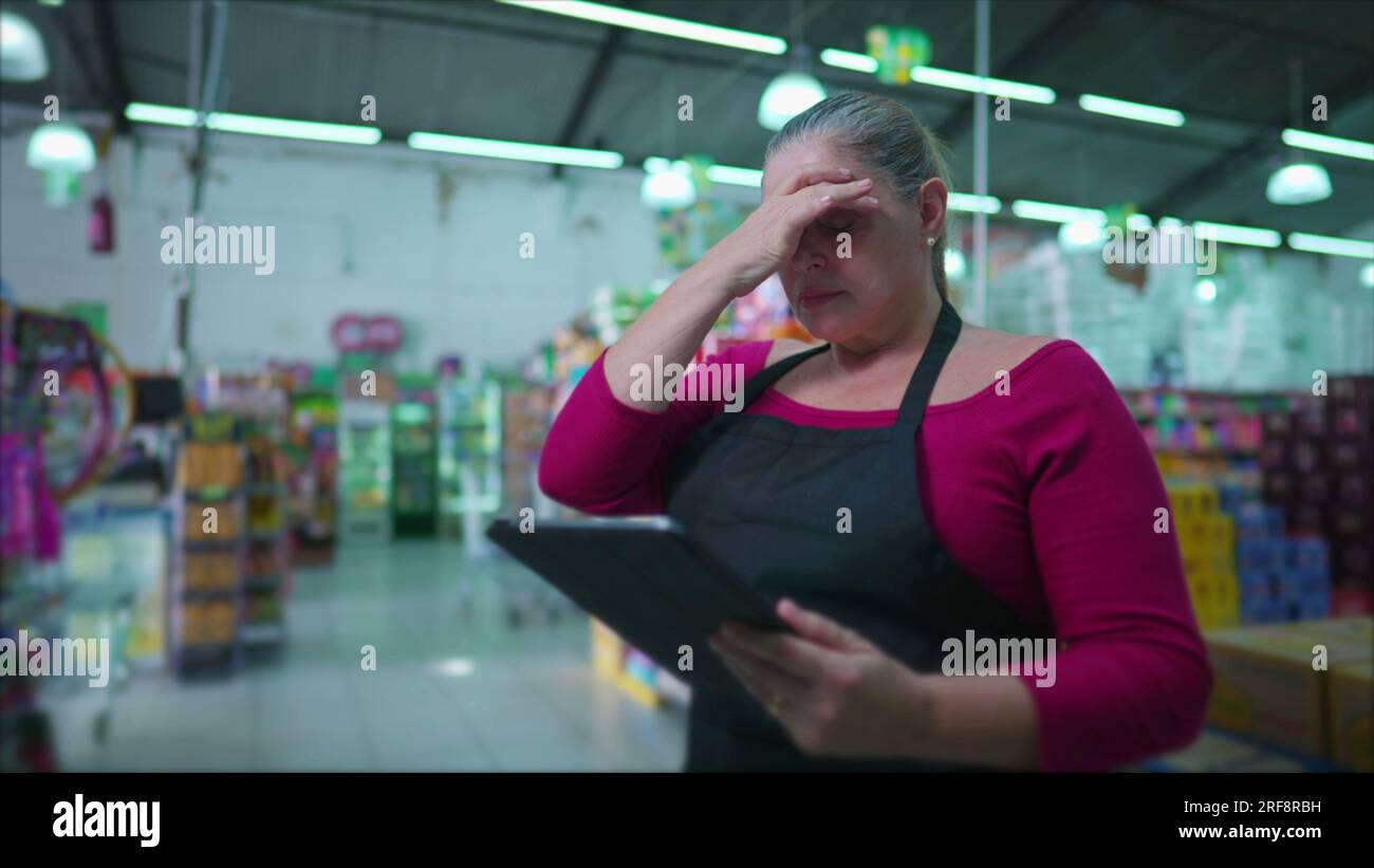 Stressed female employee of Supermarket chain standing inside business ...