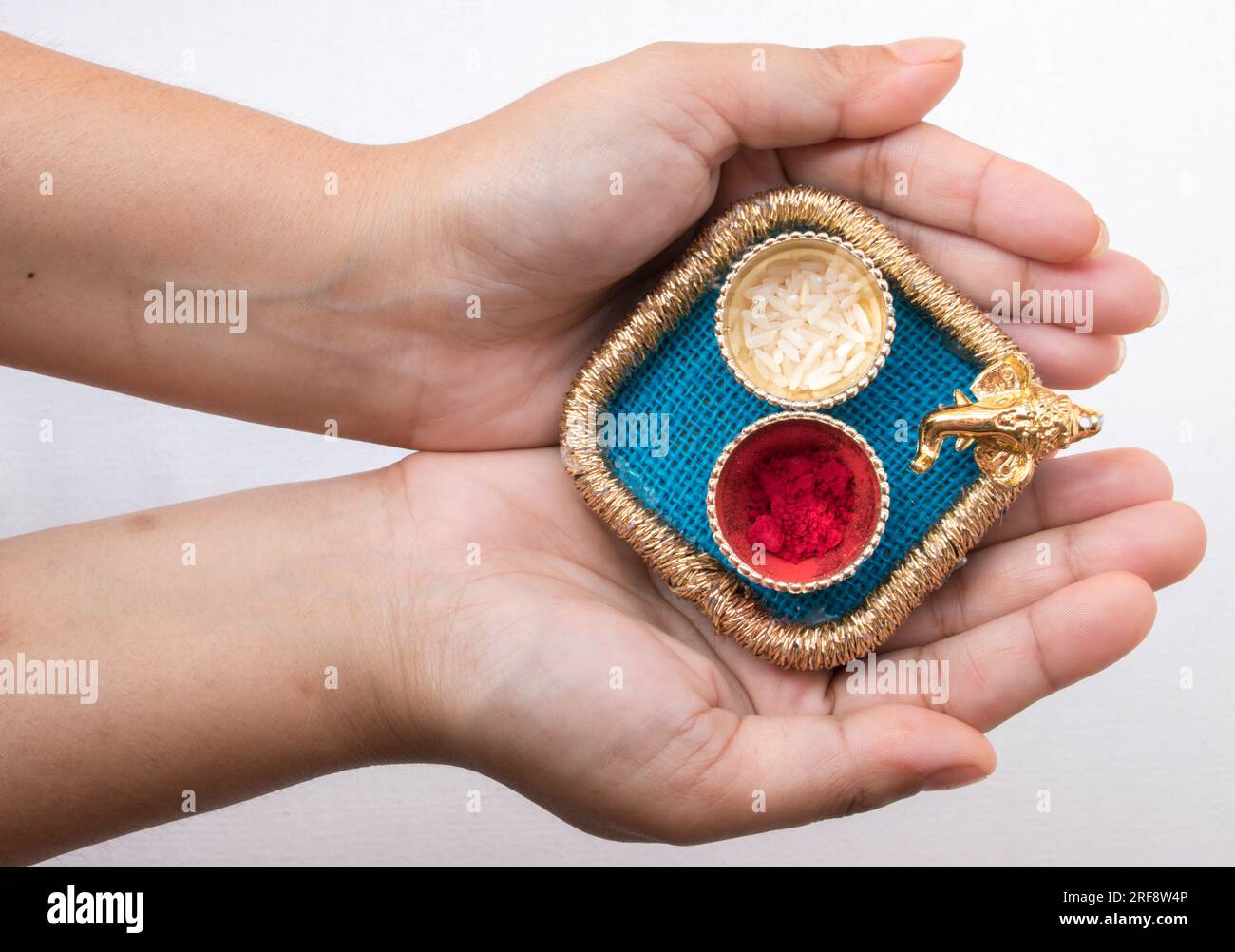 Hand holding beautiful small pooja thali having God Ganesh face, red ...