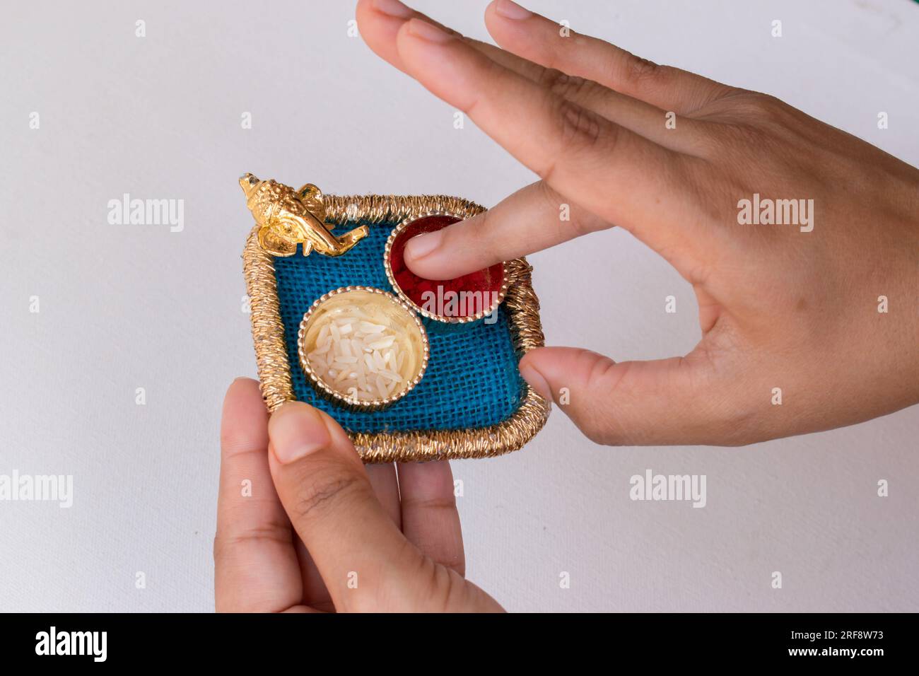 Hand holding beautiful small pooja thali having God Ganesh face, red ...