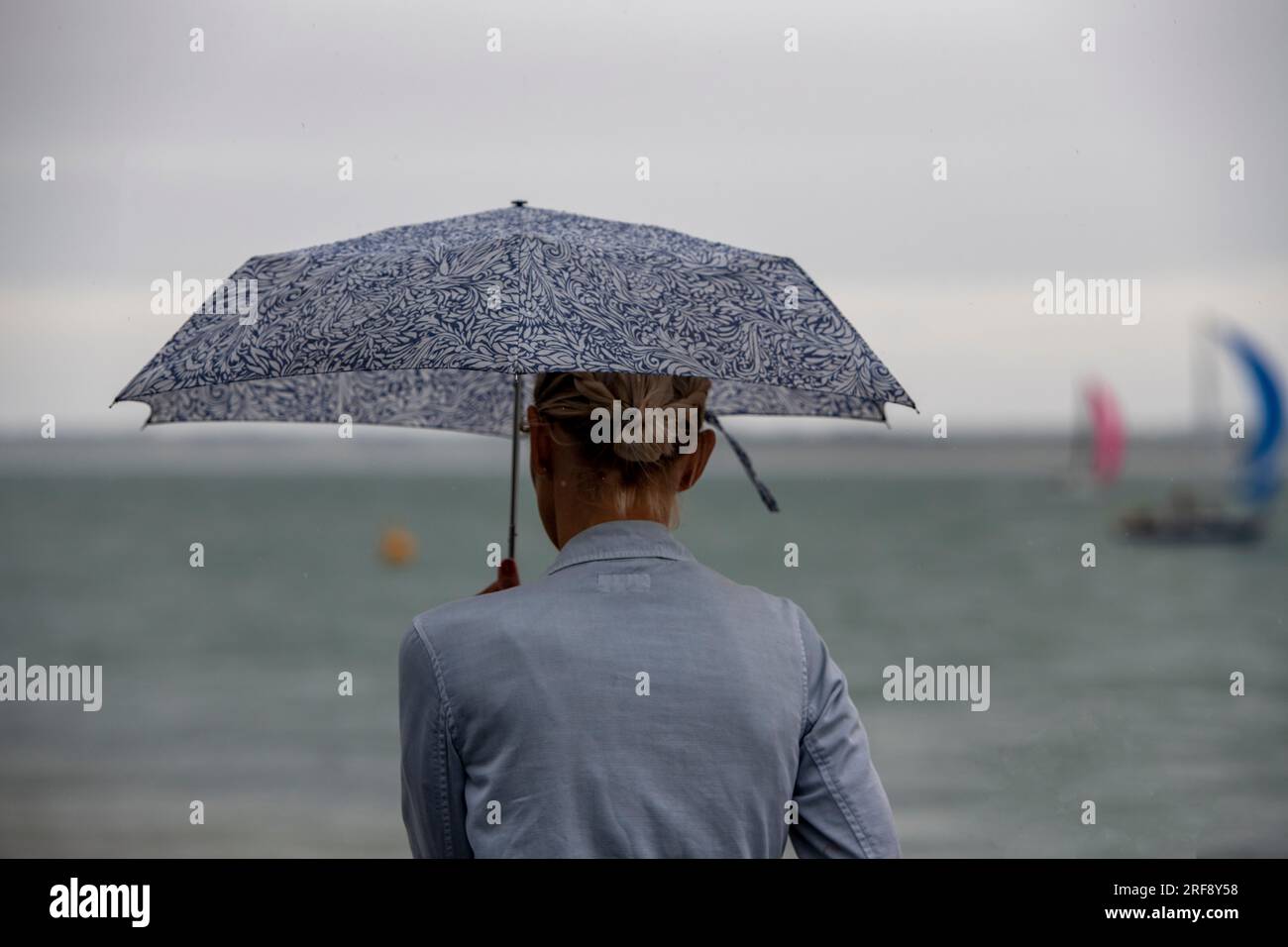 well dressed lady standing in the rain using an umbrella for shelter at ...