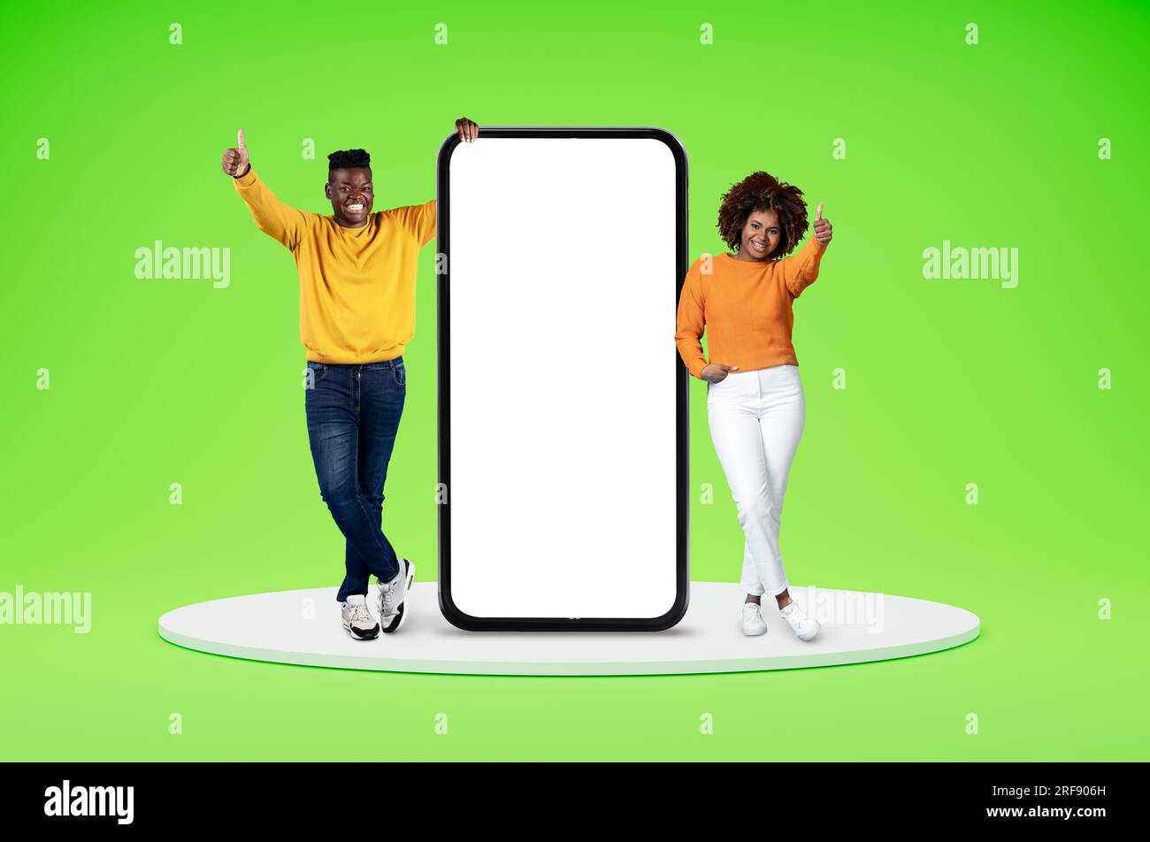 Happy black couple standing by huge phone, showing thumb up Stock Photo ...