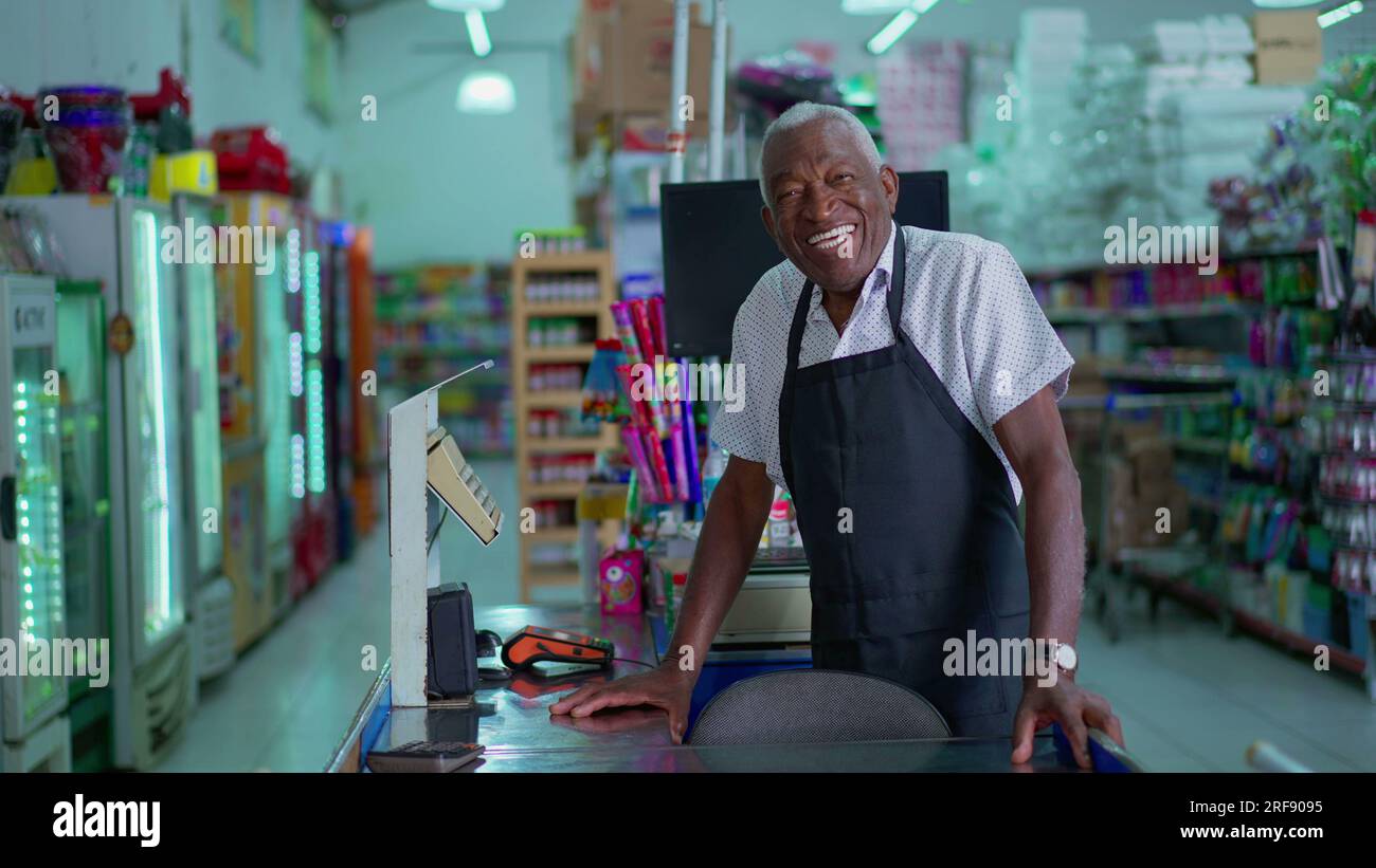 One happy black senior employee standing at supermarket cashier smiling ...