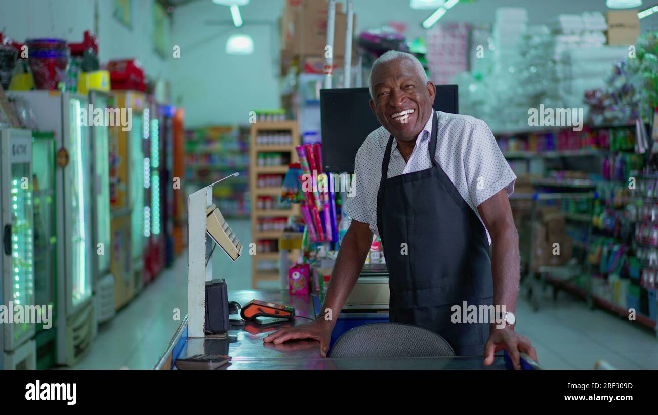 One happy black senior employee standing at supermarket cashier smiling ...