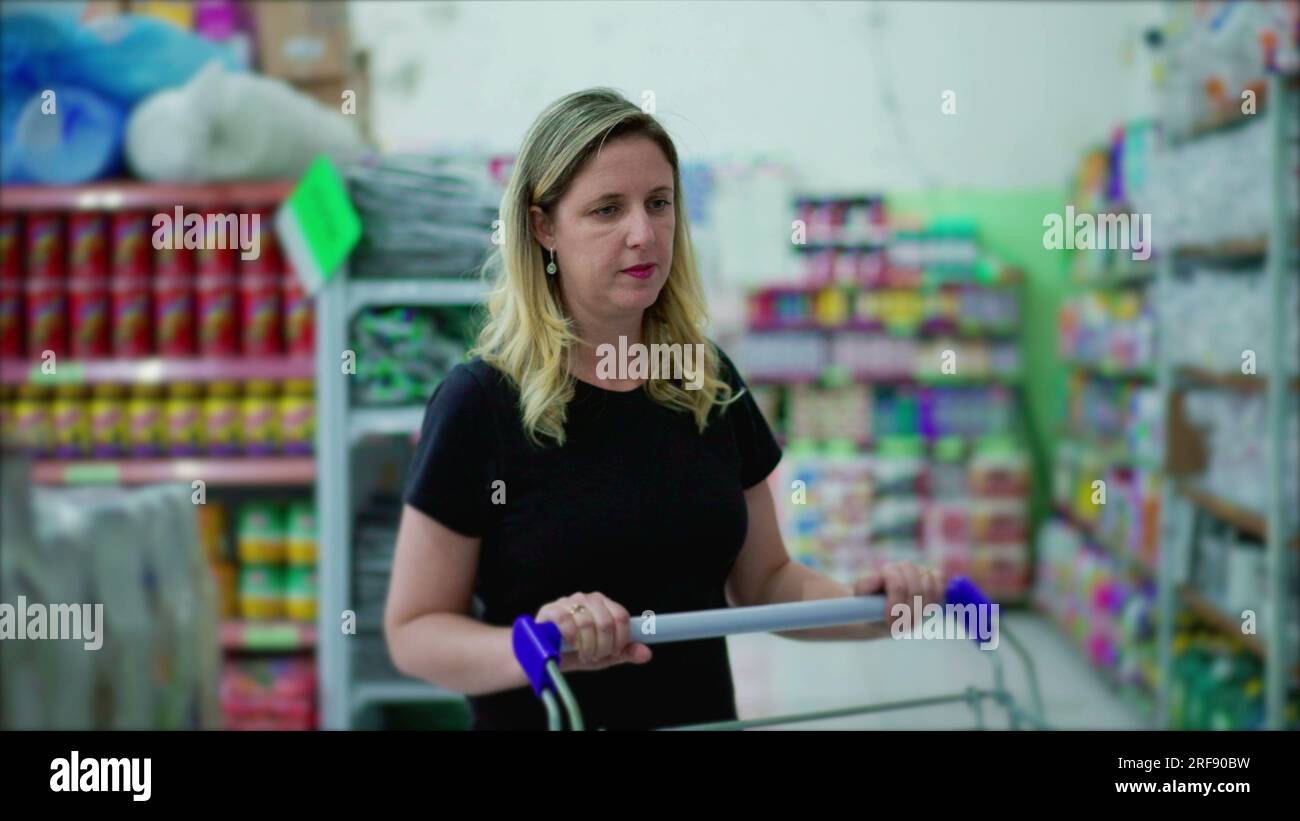 Female Shopper Browsing Products in Supermarket Aisle with Shopping ...