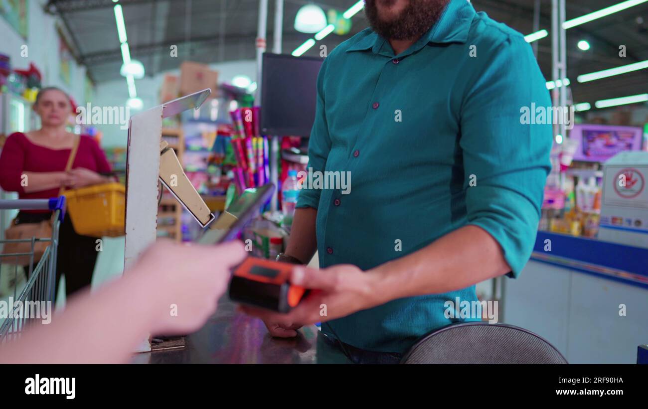 Employee cashier at supermarket doing payment procedure with ...