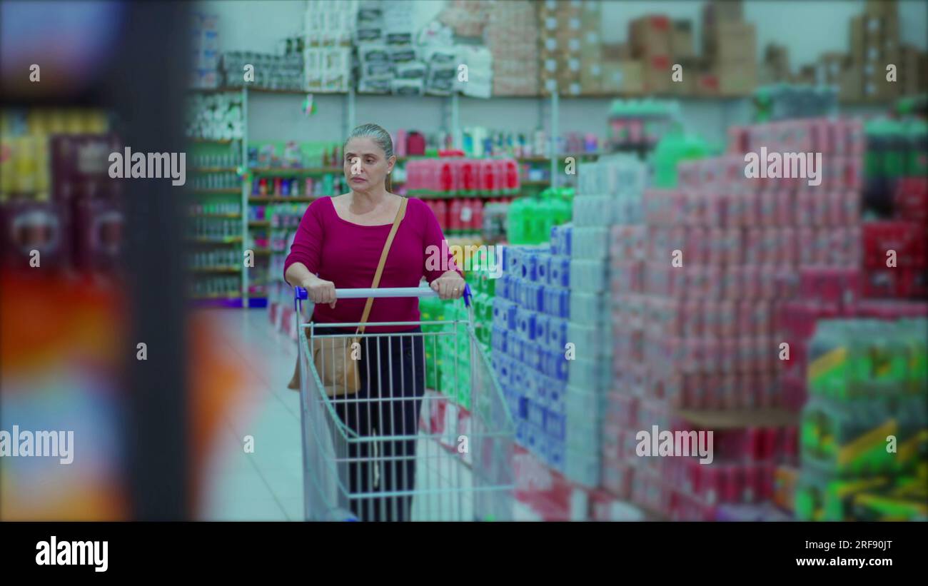 Female consumer walking in supermarket aisle browsing products on shelf ...