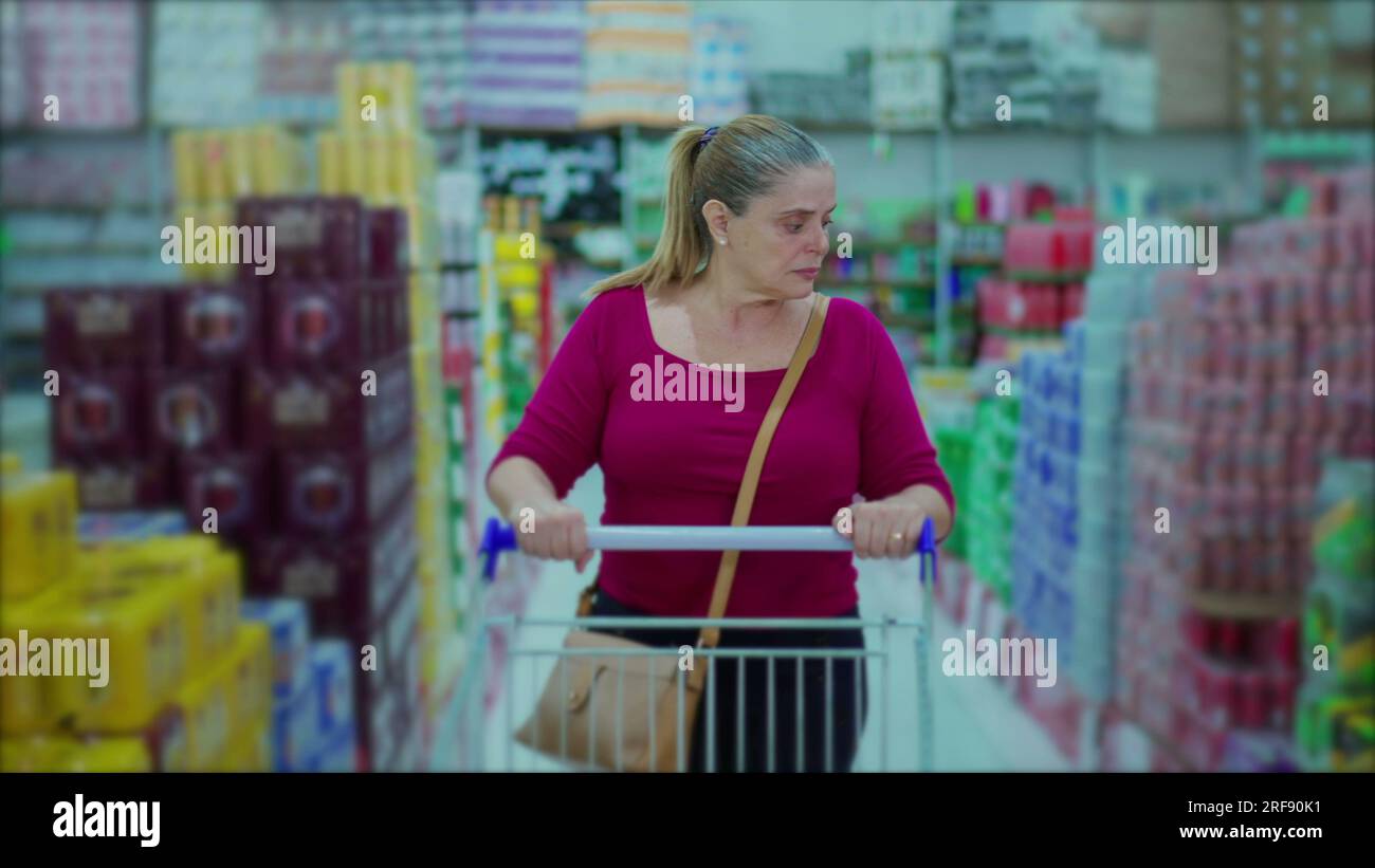 Female consumer walking in supermarket aisle browsing products on shelf ...
