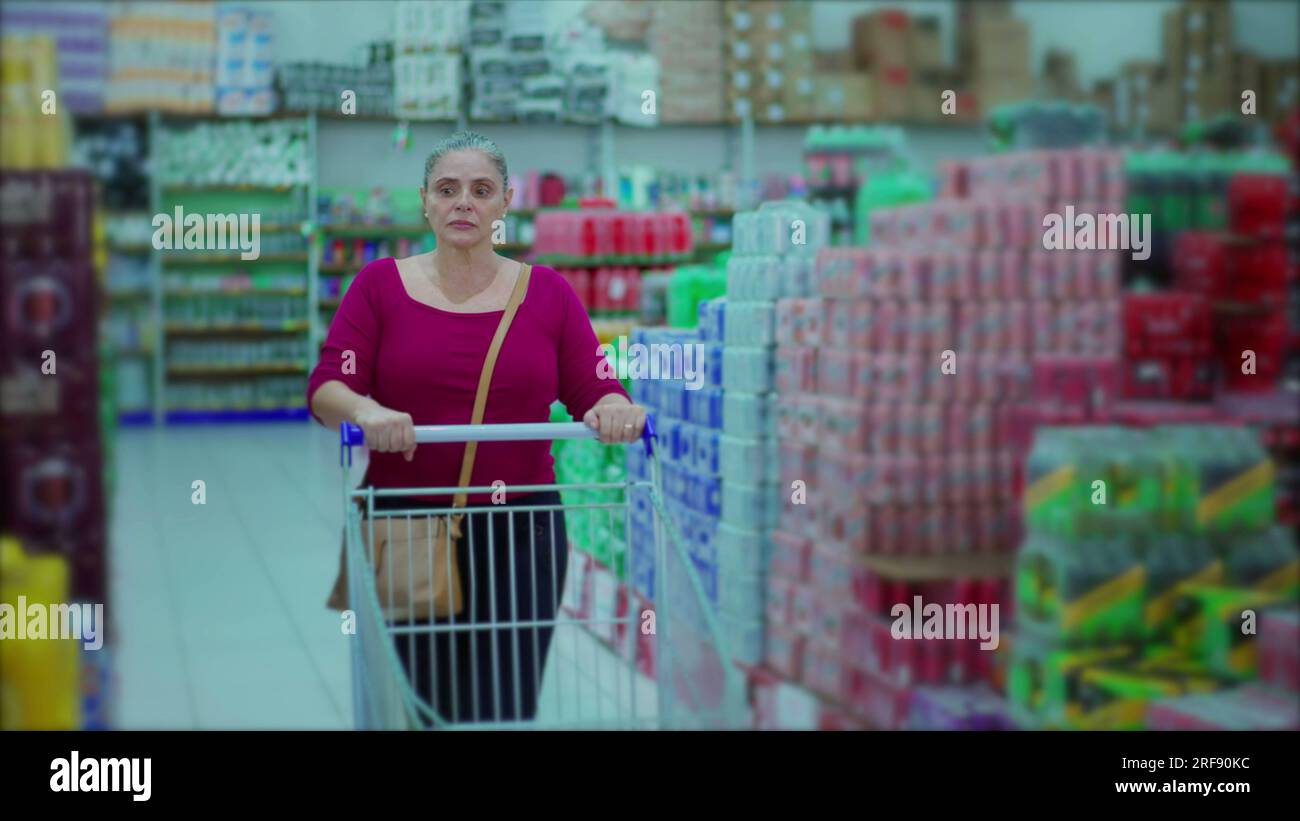 Female consumer walking in supermarket aisle browsing products on shelf ...