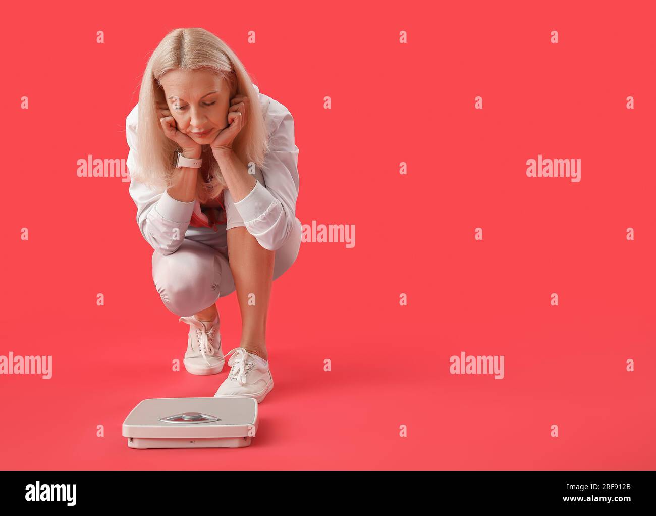 Sad mature woman with scales on red background Stock Photo - Alamy