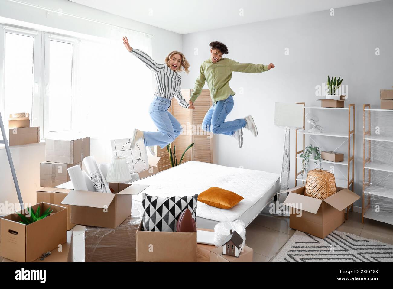 Young couple jumping in bedroom on moving day Stock Photo - Alamy