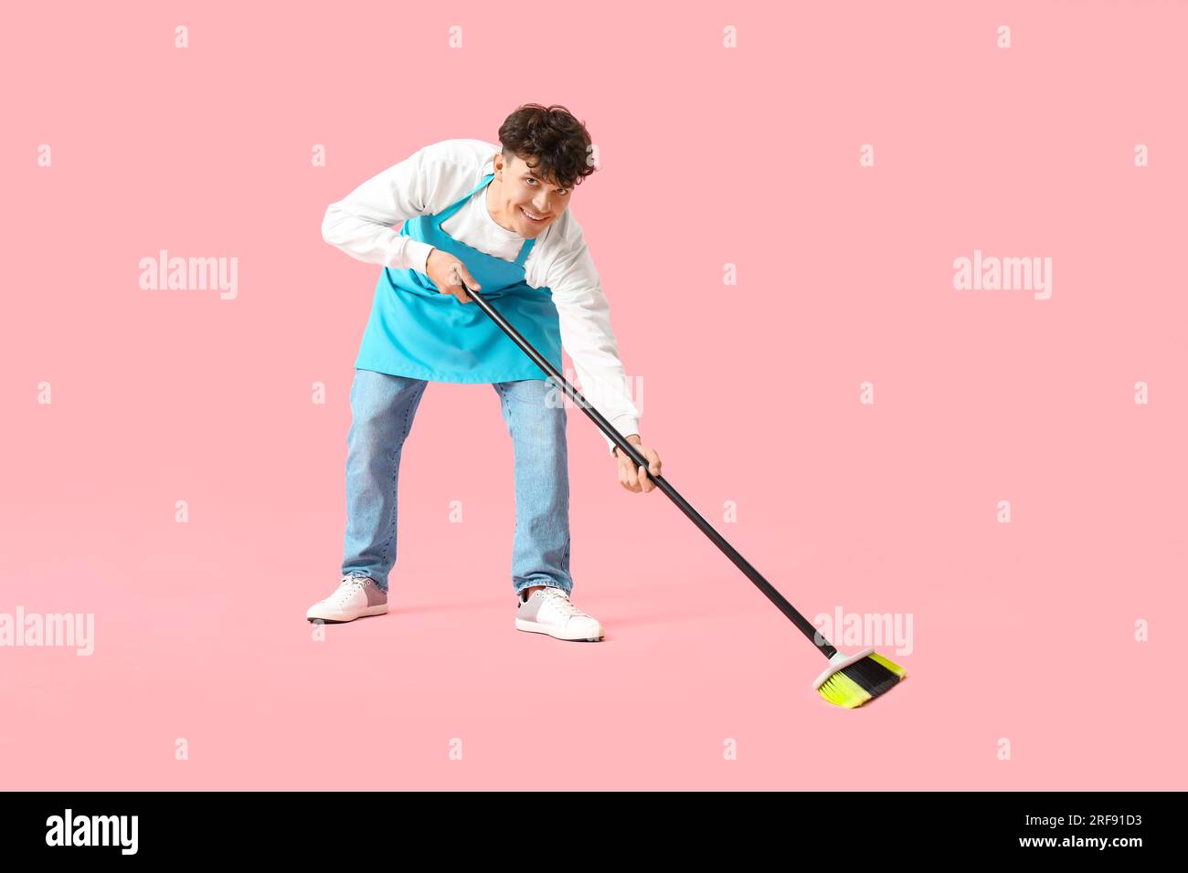 Male janitor with broom on pink background Stock Photo - Alamy