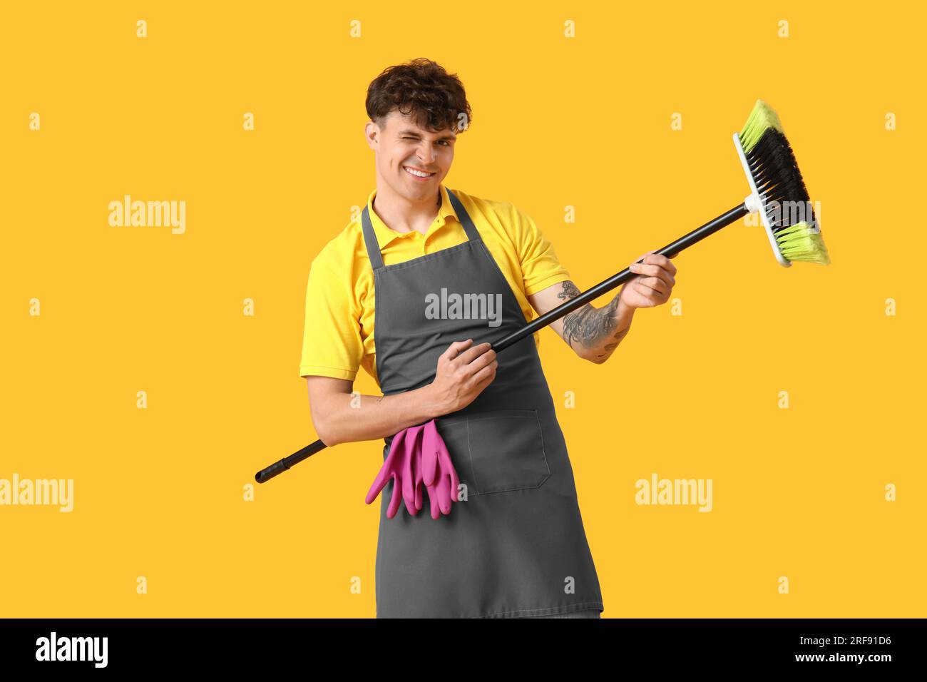 Male janitor playing with broom on yellow background Stock Photo - Alamy