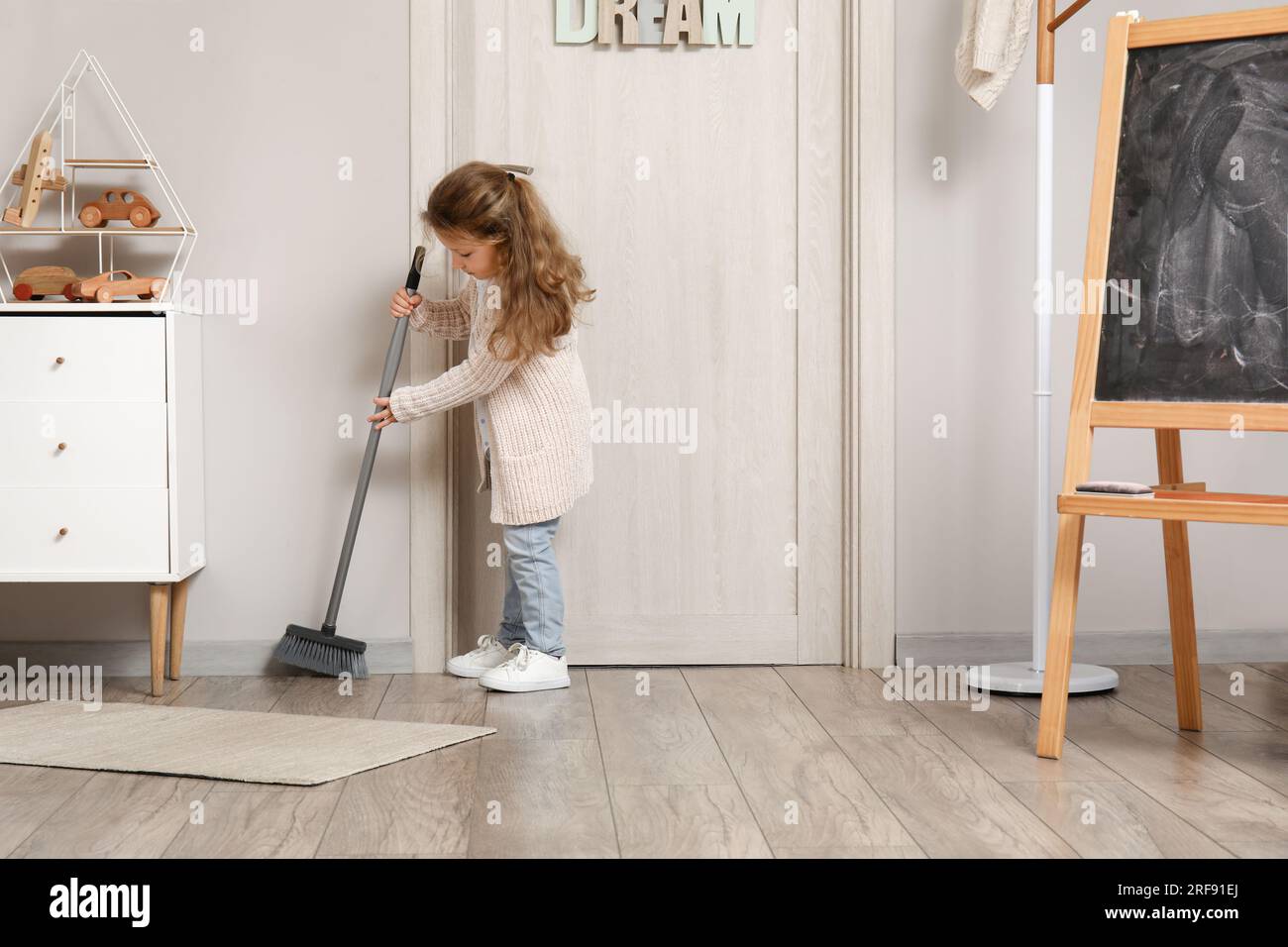 Cute little girl sweeping floor with broom at home Stock Photo - Alamy