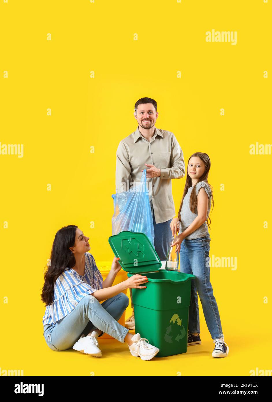 Family sorting garbage in recycle bin on yellow background Stock Photo ...