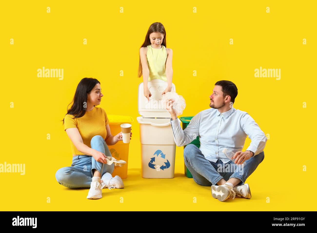 Family sorting garbage in recycle bins on yellow background Stock Photo ...