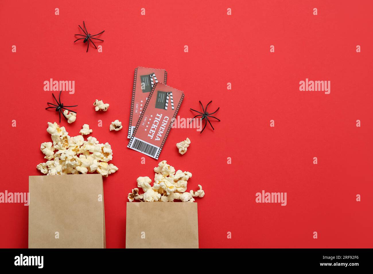 Composition with tasty popcorn, spiders and cinema tickets on red ...