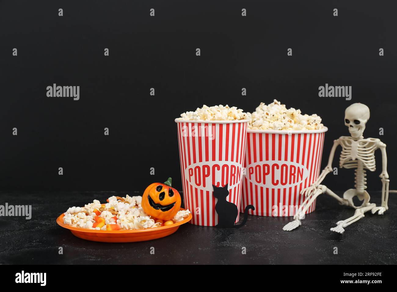 Composition with tasty popcorn and skeleton on dark background ...
