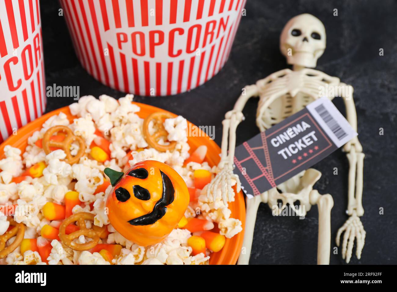 Plate with tasty popcorn, candy corns, pretzels. skeleton and cinema ...