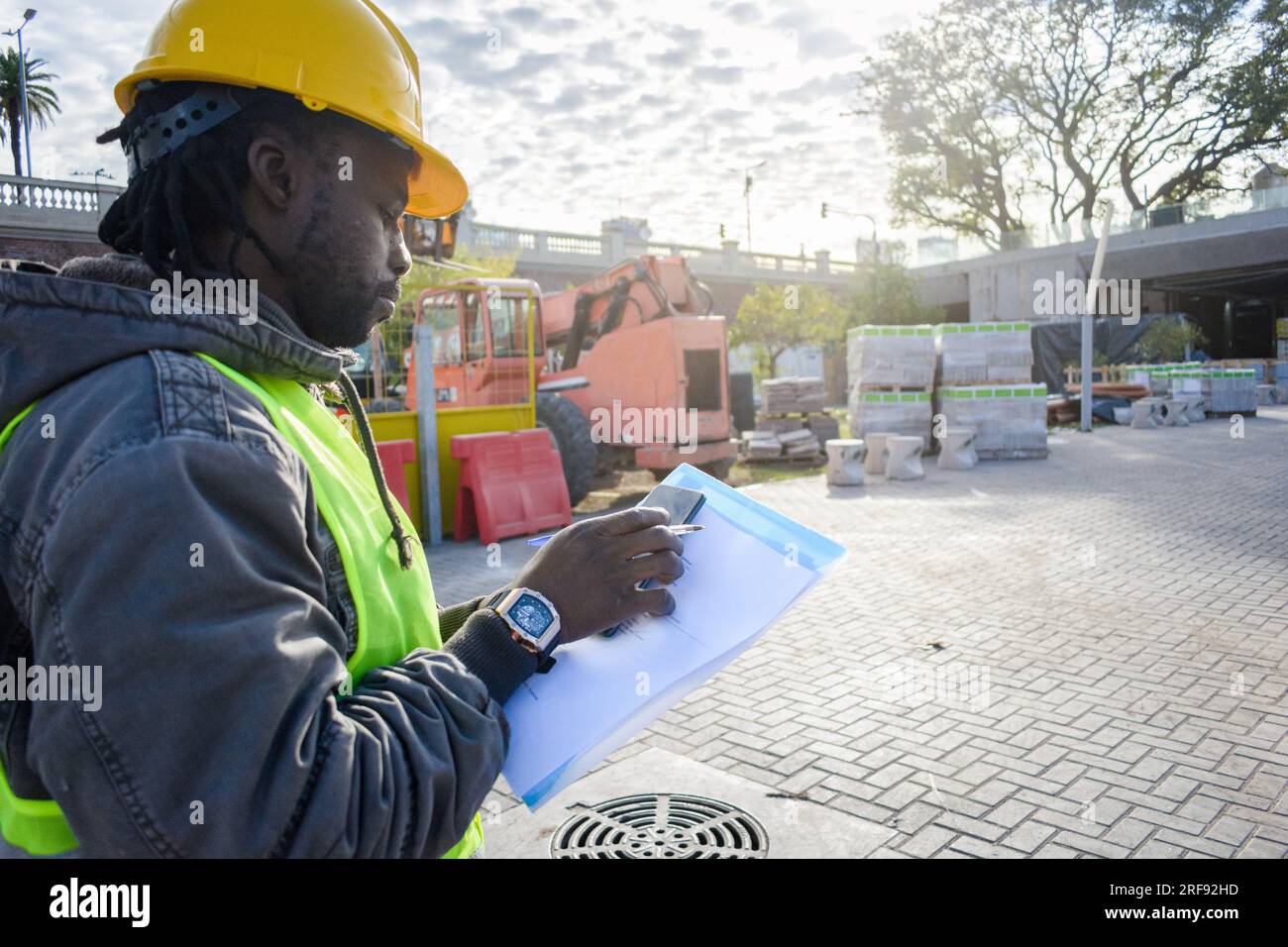 rear view of young black man in yellow safety helmet, vest and beard ...