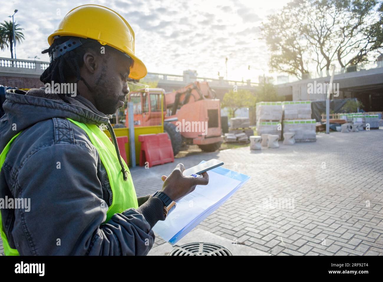 rear view of young black man in yellow safety helmet, vest and beard ...