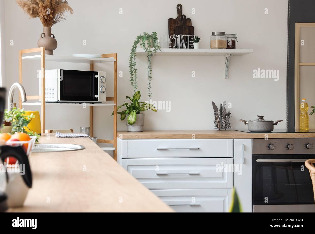 Interior of modern kitchen with white counters and microwave oven on ...