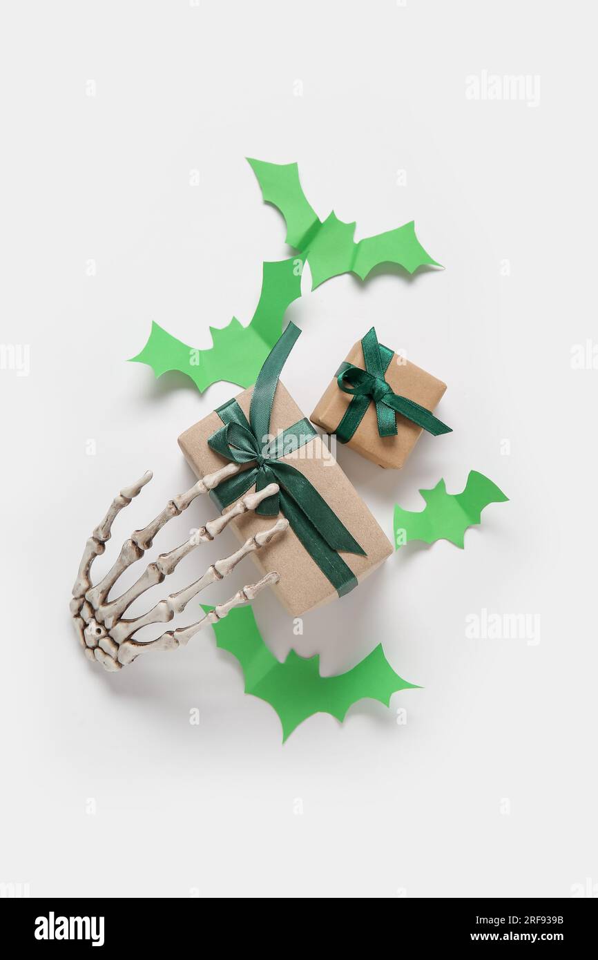Composition with beautiful gift boxes, skeleton hand and bats made of ...