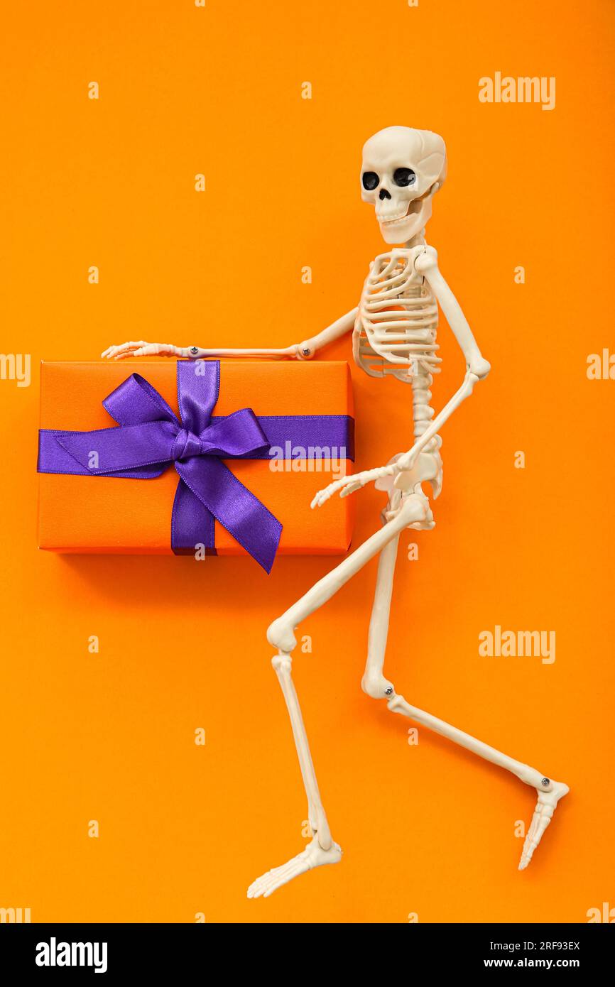Composition with skeleton and gift box for Halloween on orange ...