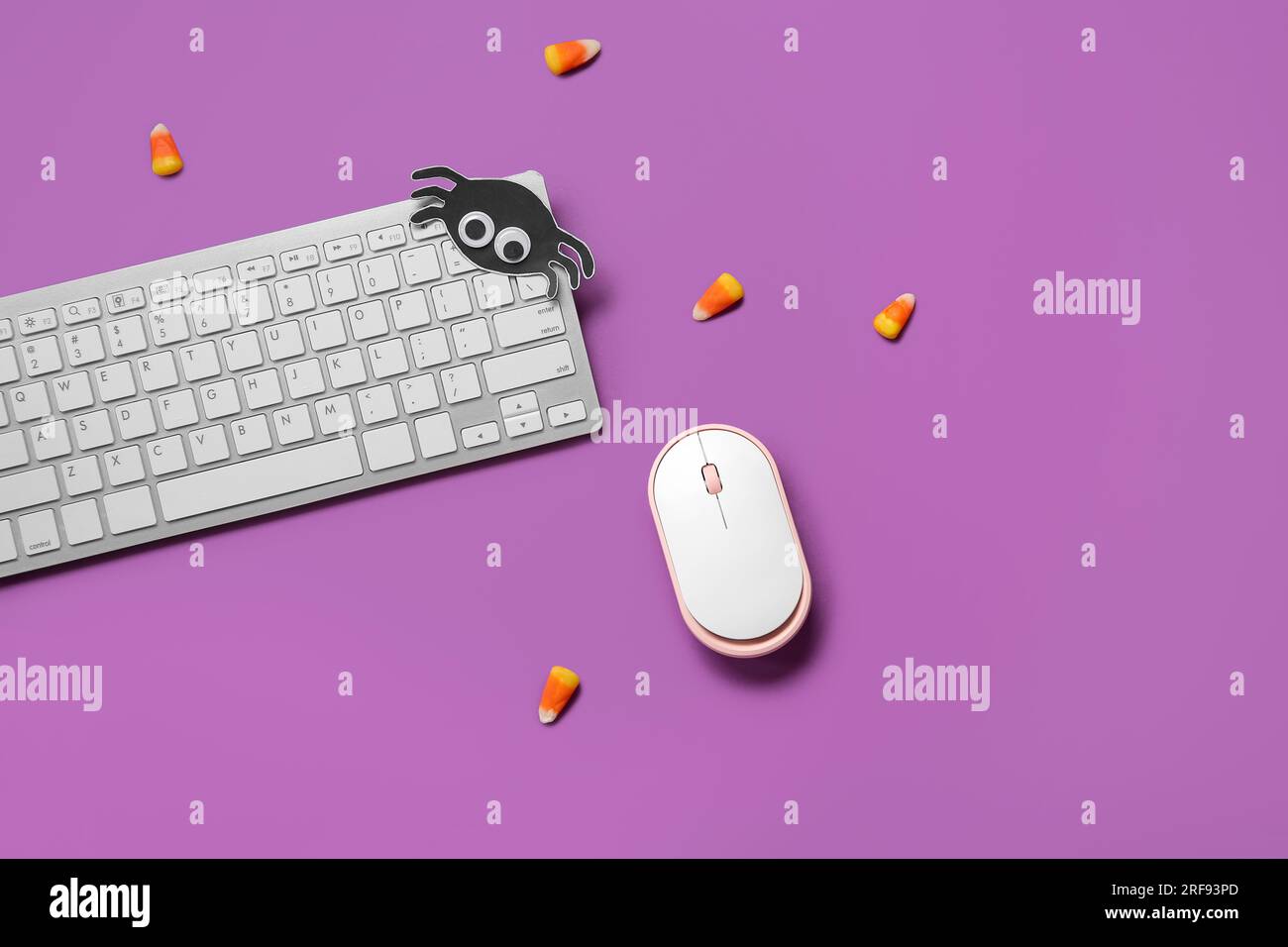 Composition with modern computer keyboard, mouse and tasty candy corns ...