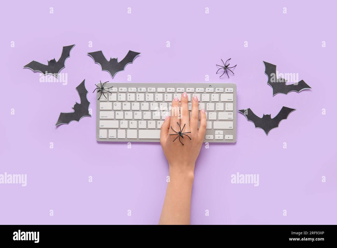 Female hand with modern computer keyboard, spiders and paper bats for ...