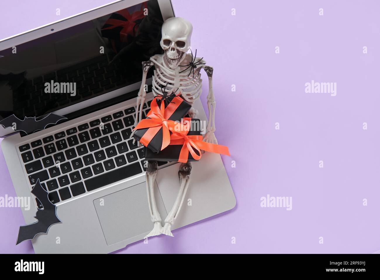 Composition with modern laptop, skeleton and gift boxes for Halloween ...