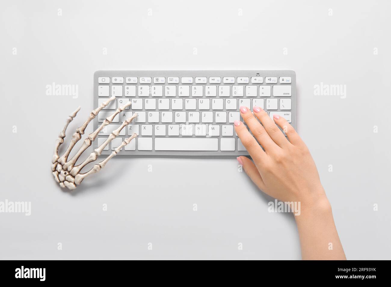 Female and skeleton hands with modern computer keyboard on white ...