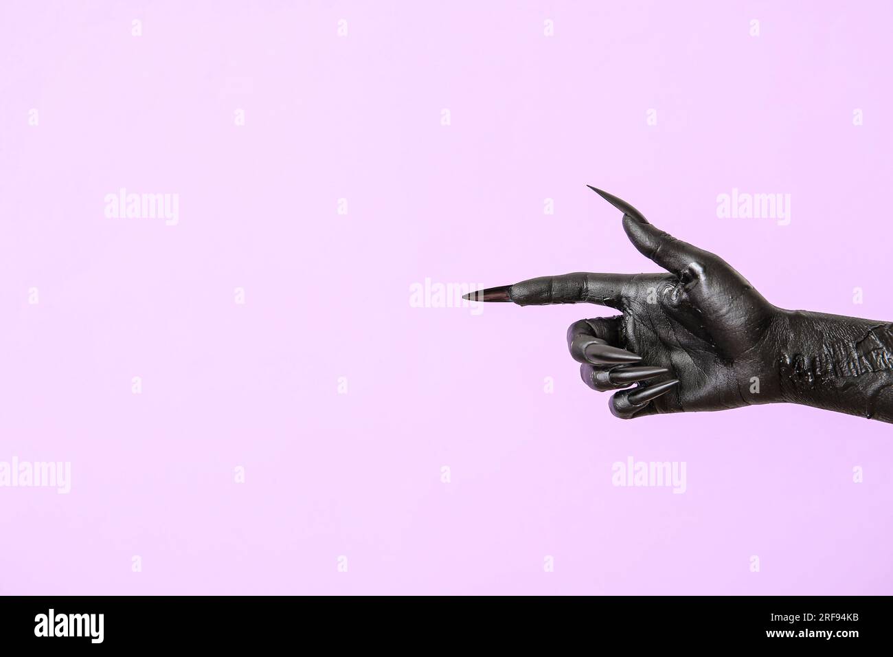 Black hand of witch pointing at something on purple background ...