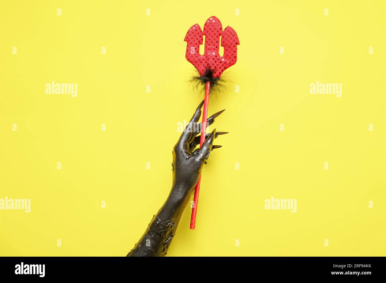 Black hand of witch with devil pitchfork on yellow background ...