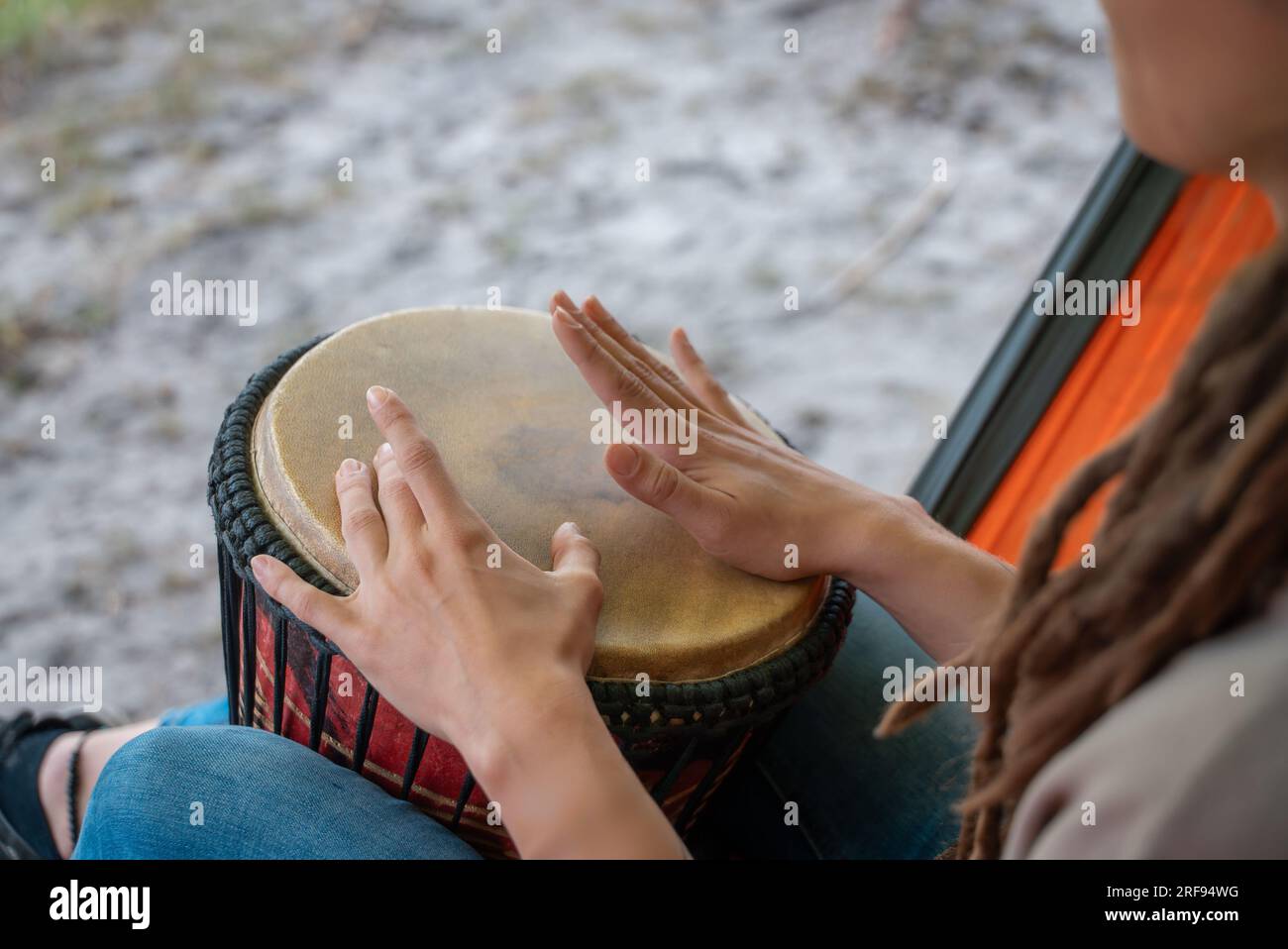 person with dreadlocks play tribal reggae at small African hand drum ...