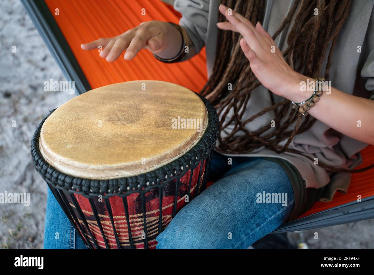 person with dreadlocks play tribal reggae at small African hand drum ...