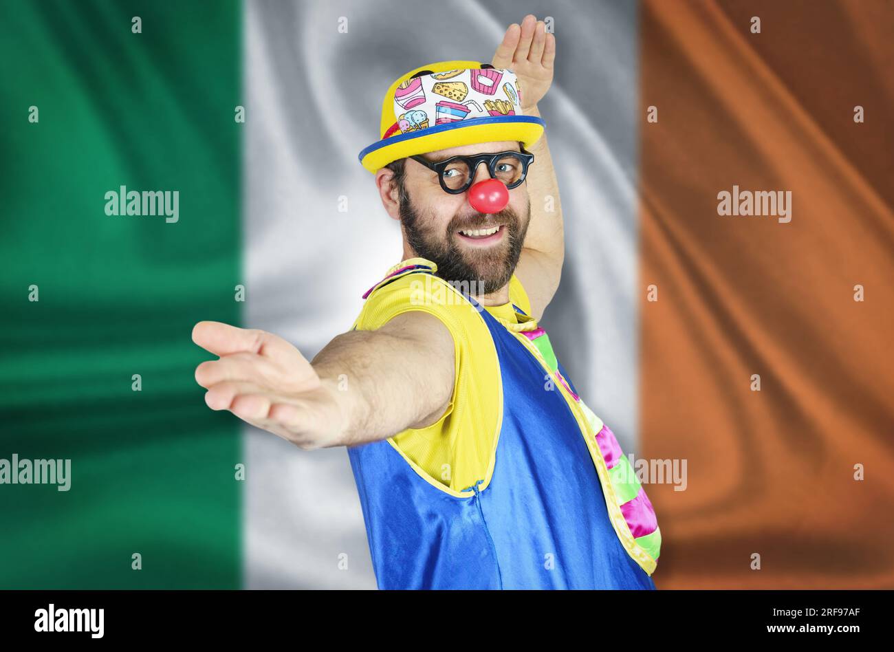 A cheerful clown stands in a welcoming pose against the background of ...