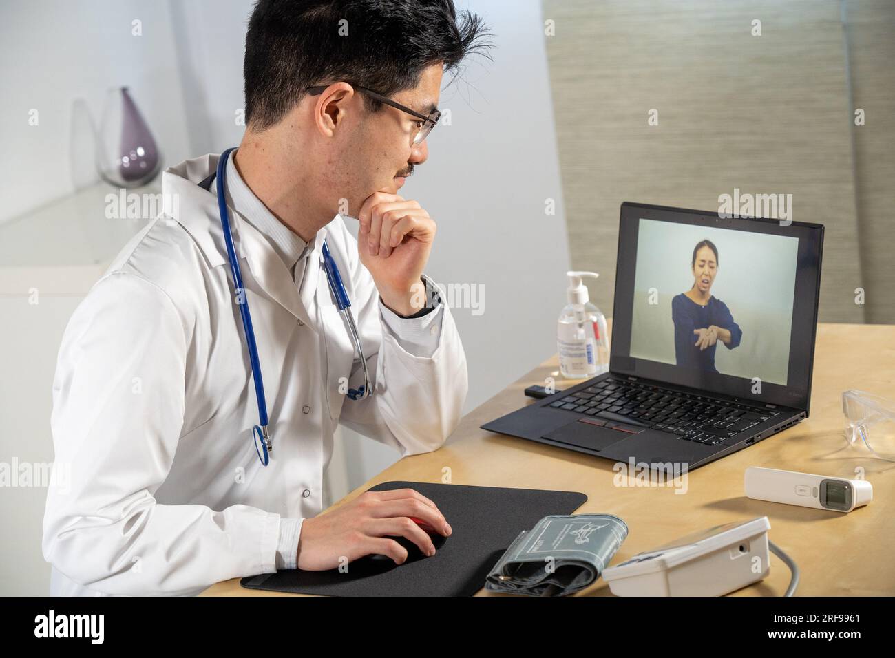 Doctor in remote consultation with 30 year old female patient with pain in her hand Stock Photo ...