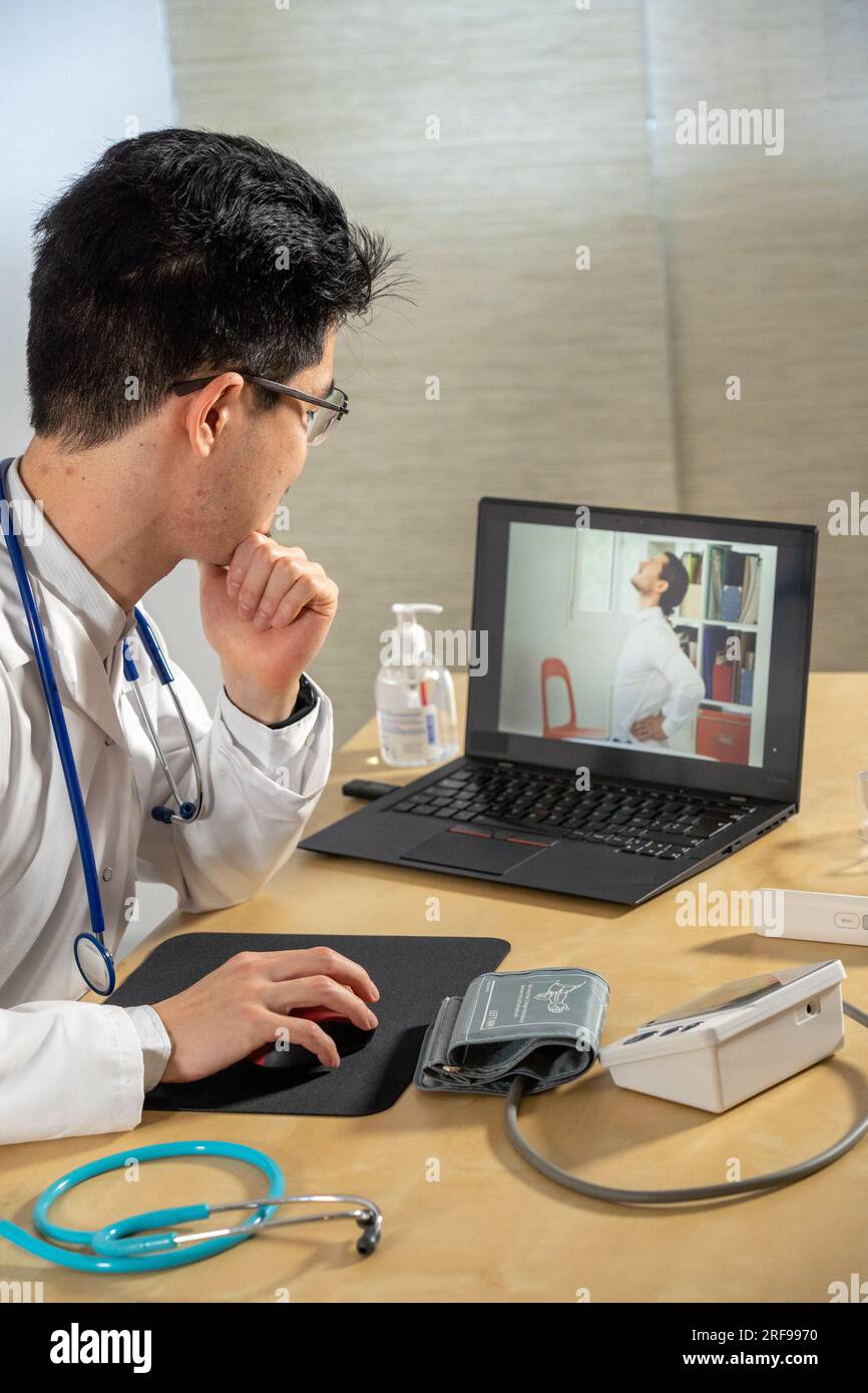 Doctor in remote consultation with 30 year old patient with back pain Stock Photo - Alamy
