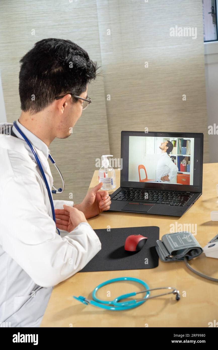 Doctor in remote consultation with 30 year old patient with back pain ...
