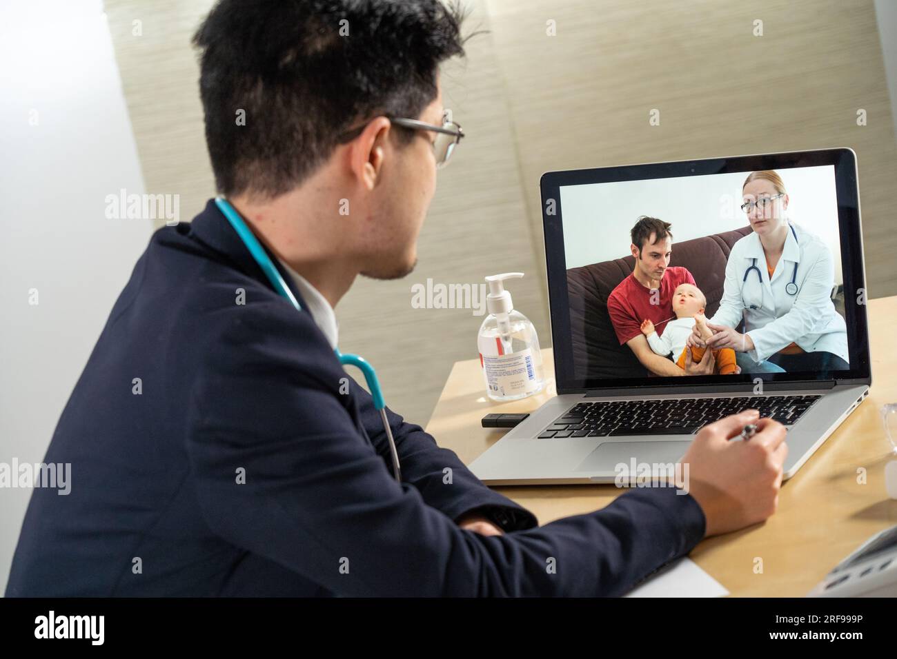 Pediatrician in remote consultation with doctor, father and infant with ...