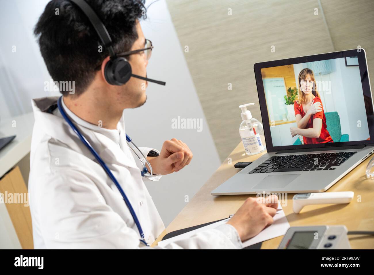 Doctor in remote consultation with 30 year old female patient with shoulder pain Stock Photo - Alamy