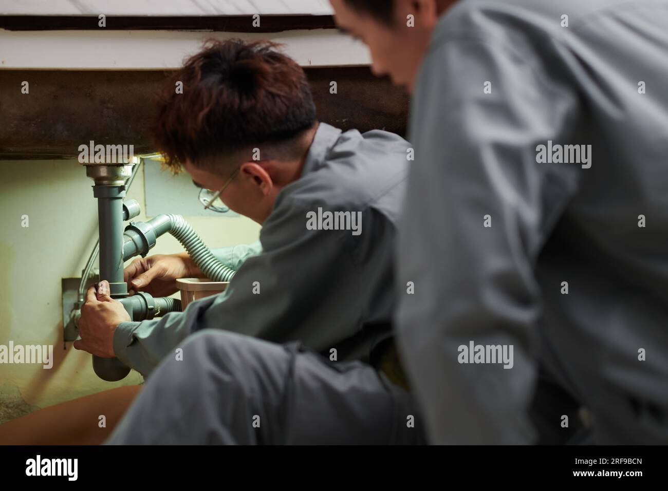 Plumbers installing new plastic pipes under kitchen sink Stock Photo ...