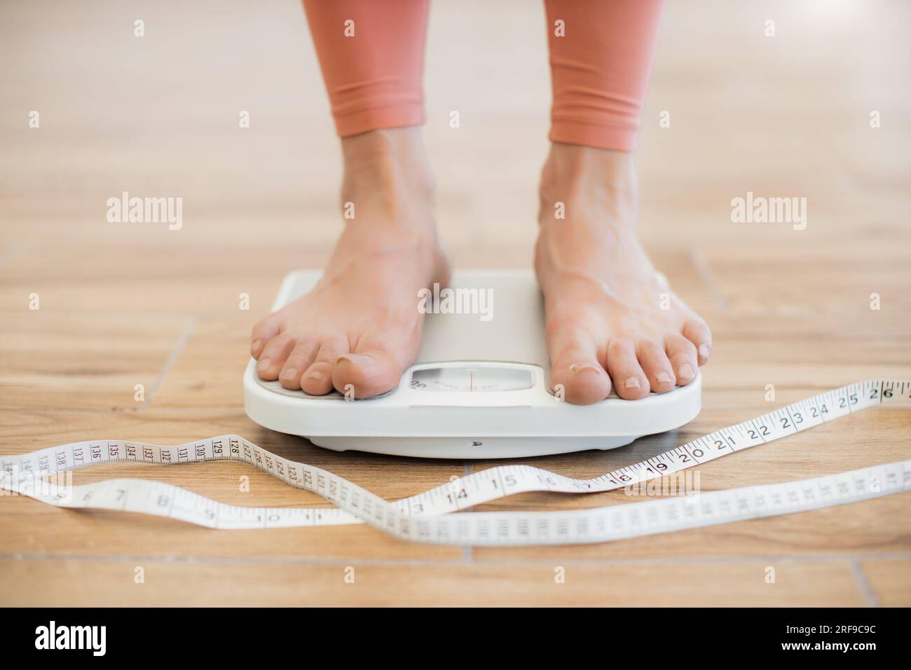 Close up view of barefoot human legs in tight-fitting terracotta pants ...